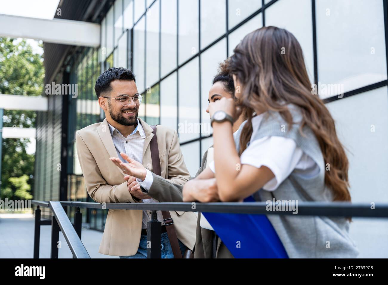 Three business people waiting in front of office building taking a ...