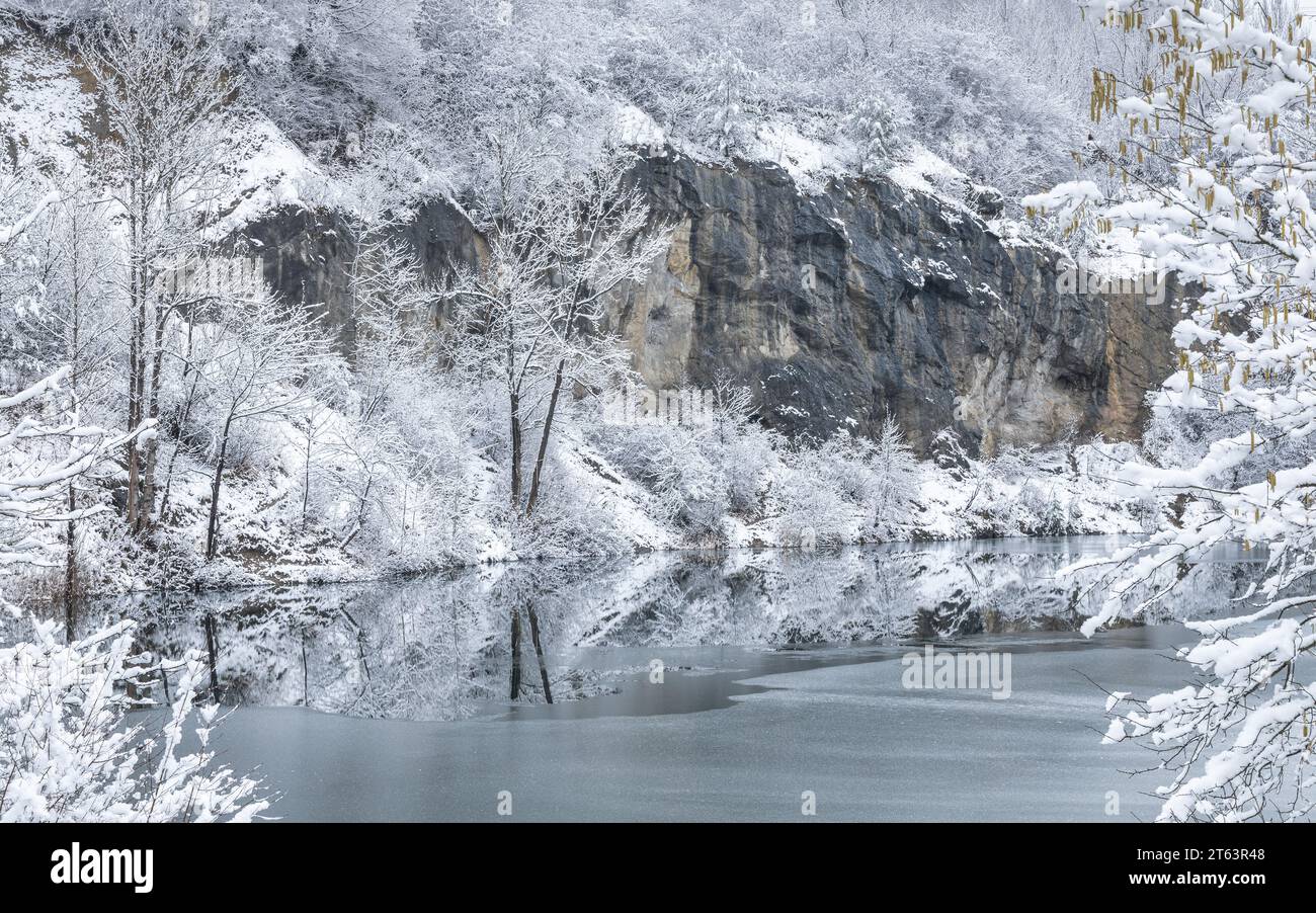 Winter snowy landscape with a lake by a rock wall Stock Photo - Alamy