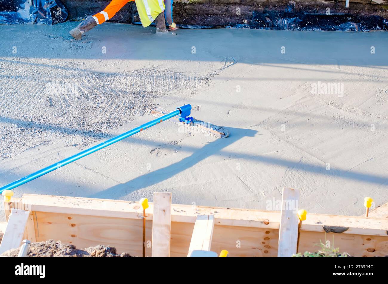 Builder using a steel pan and trowel to spread, level and smooth the ...