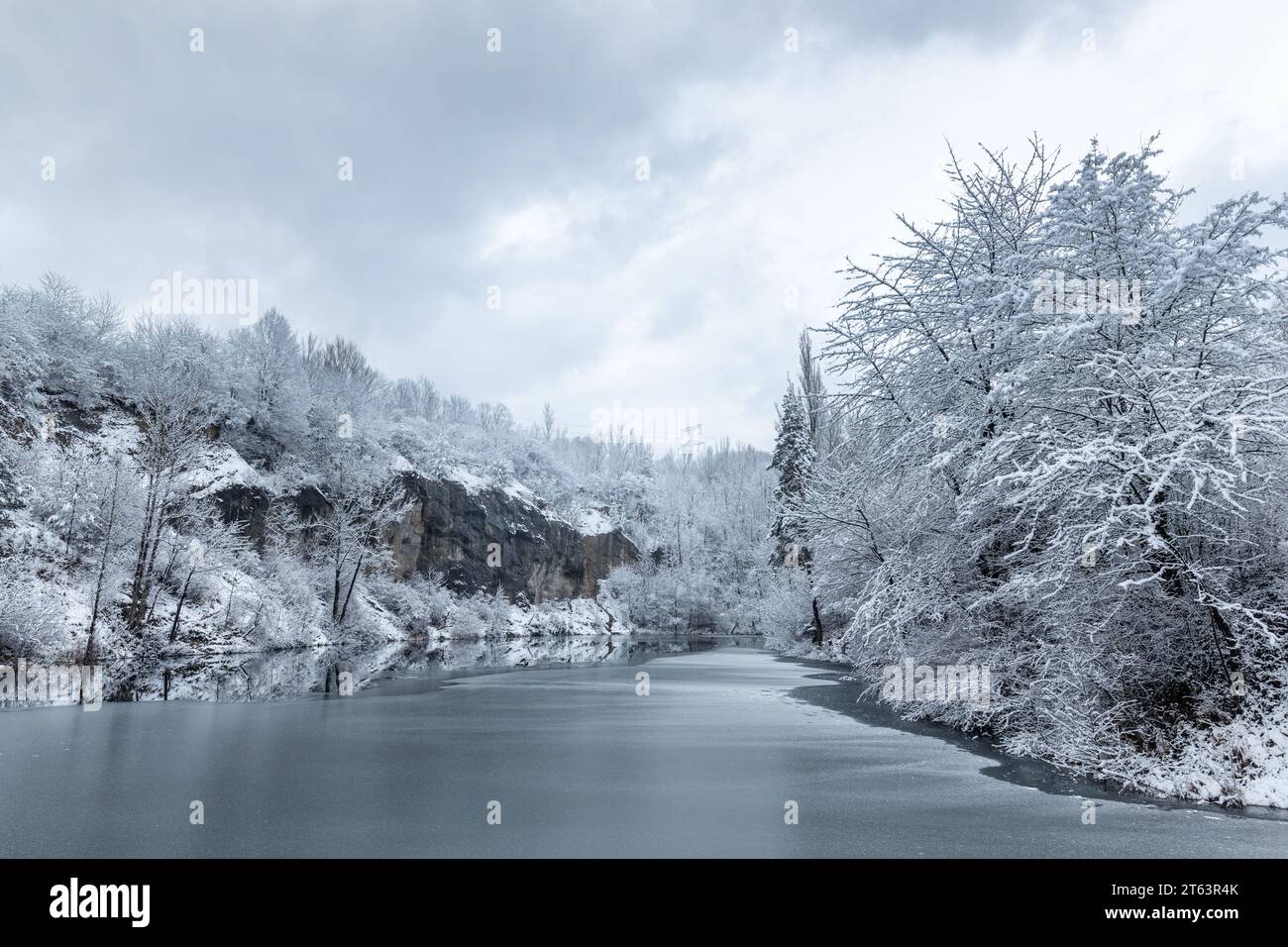 Winter snowy landscape with a lake by a rock wall Stock Photo - Alamy