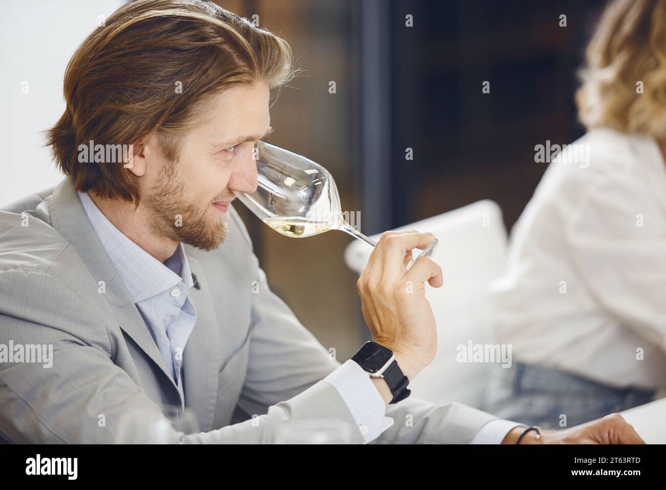 Successful looking male sommelier smelling and tasting white wine into ...