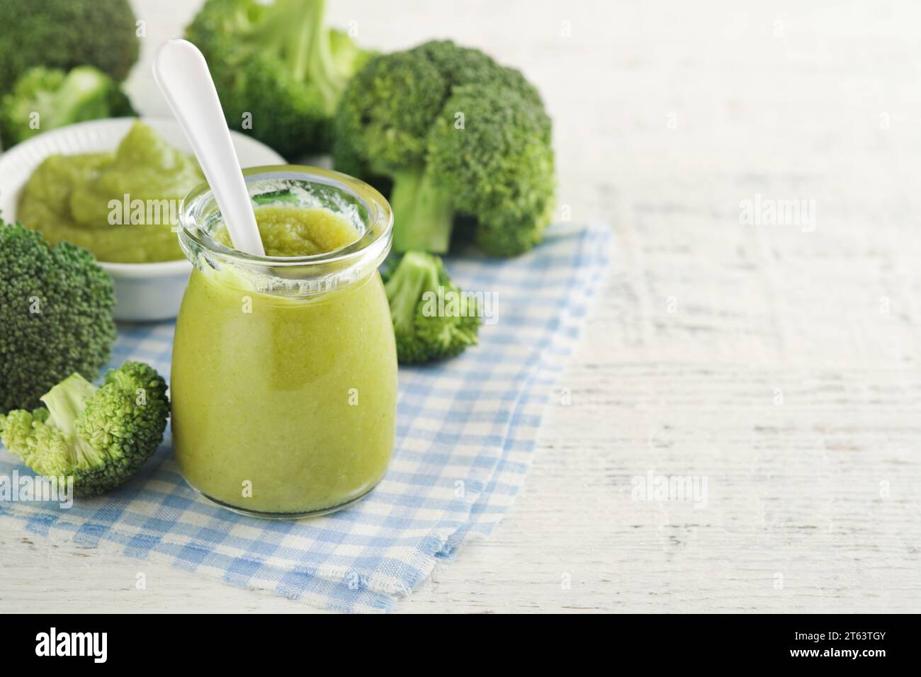 Green broccoli baby food in white bowl and jar on table. Green baby ...