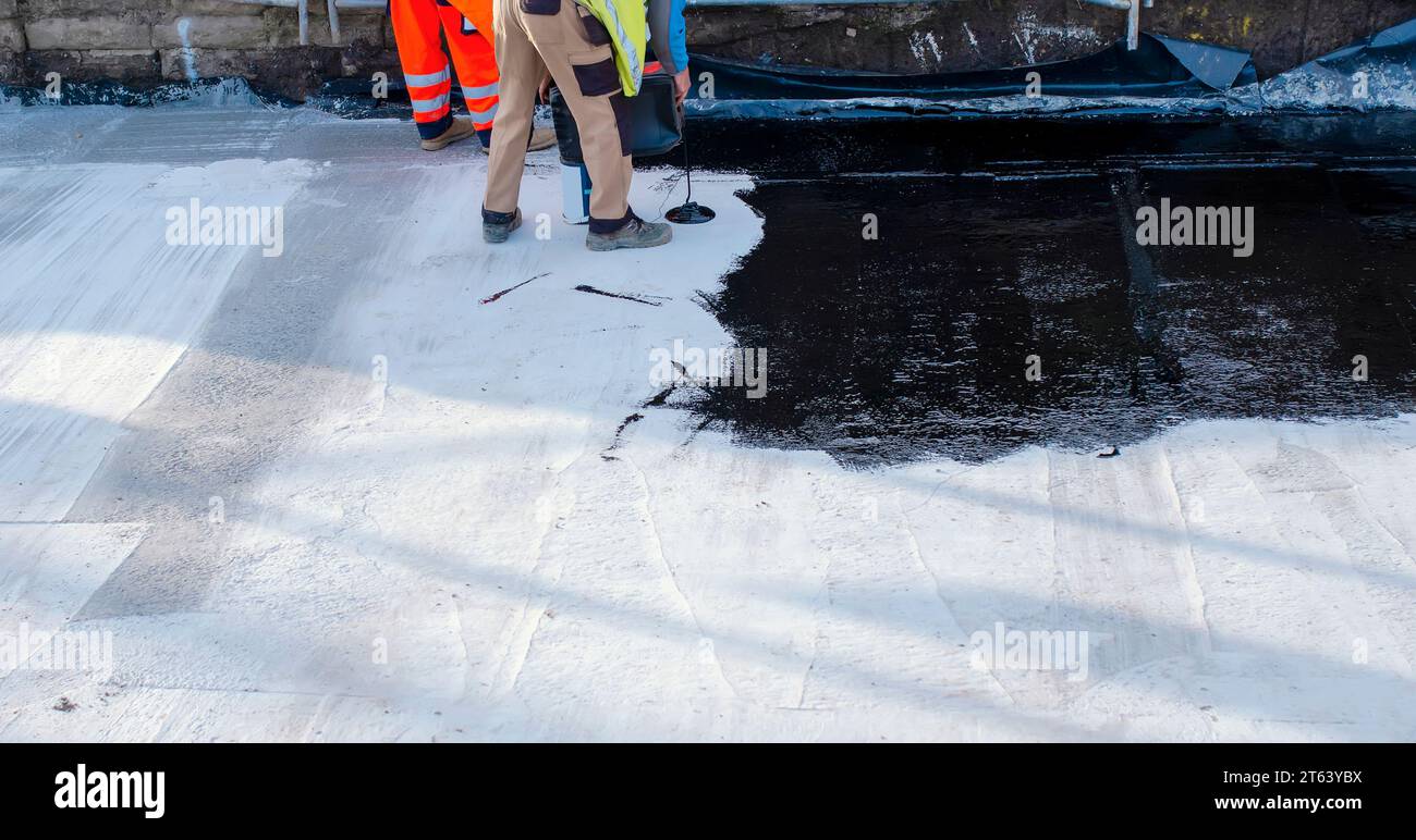 Waterproofing coating. Builder applying waterproofing bitumen mastic on ...