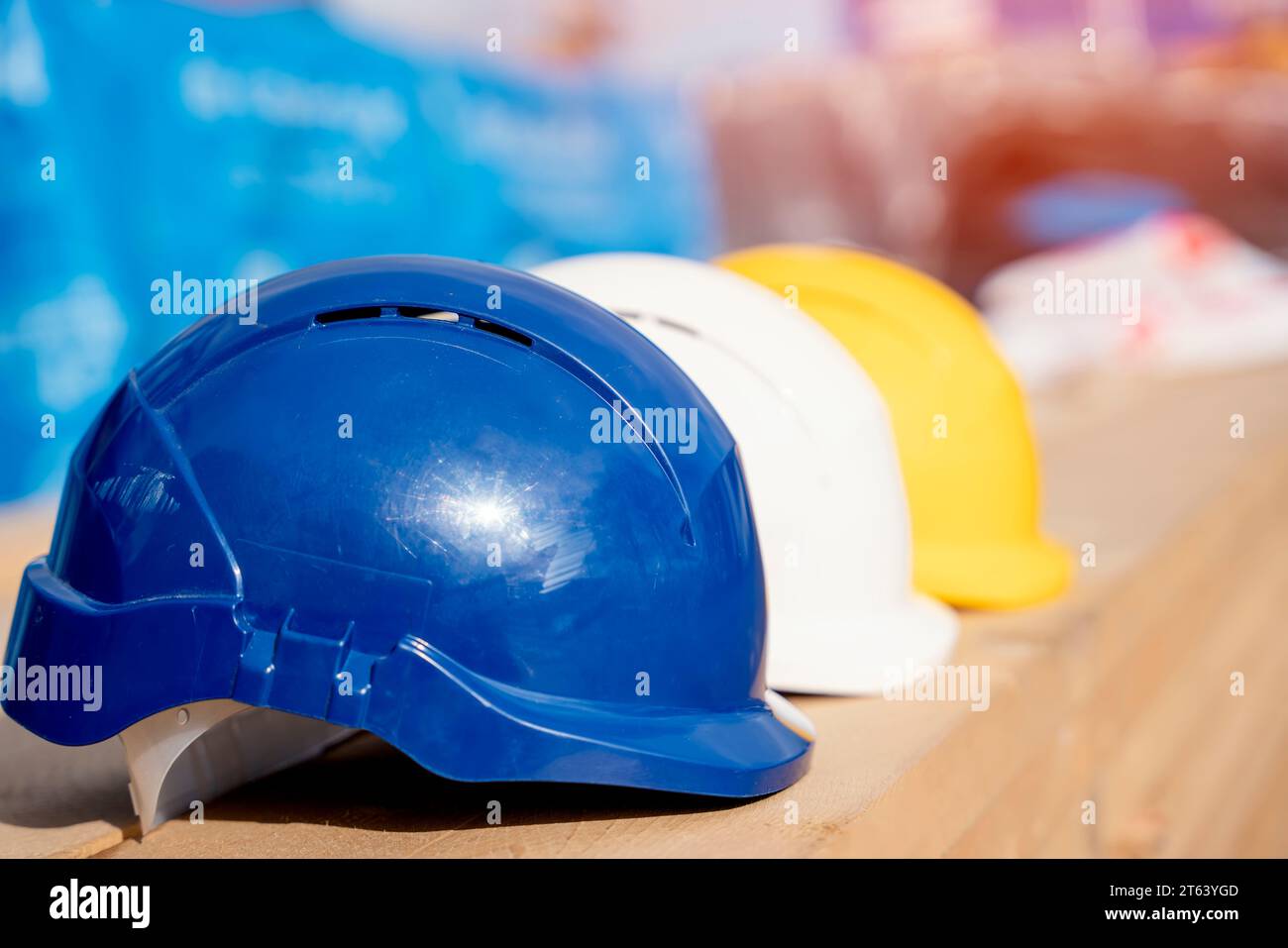 Three helmets of different colors on top of timber board close-up with ...