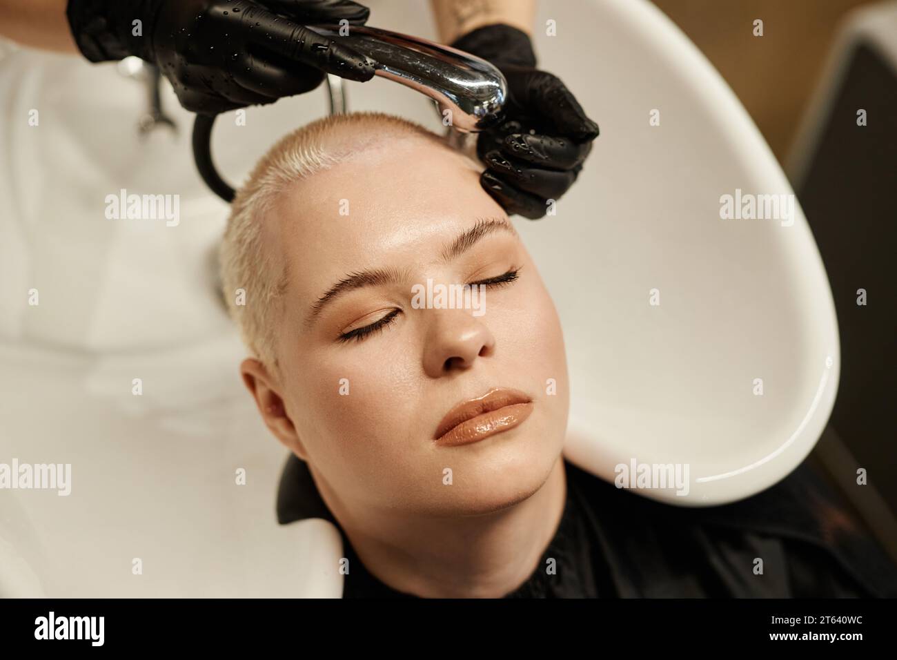 Top down portrait of young woman with buzzcut enjoying hair wash in ...
