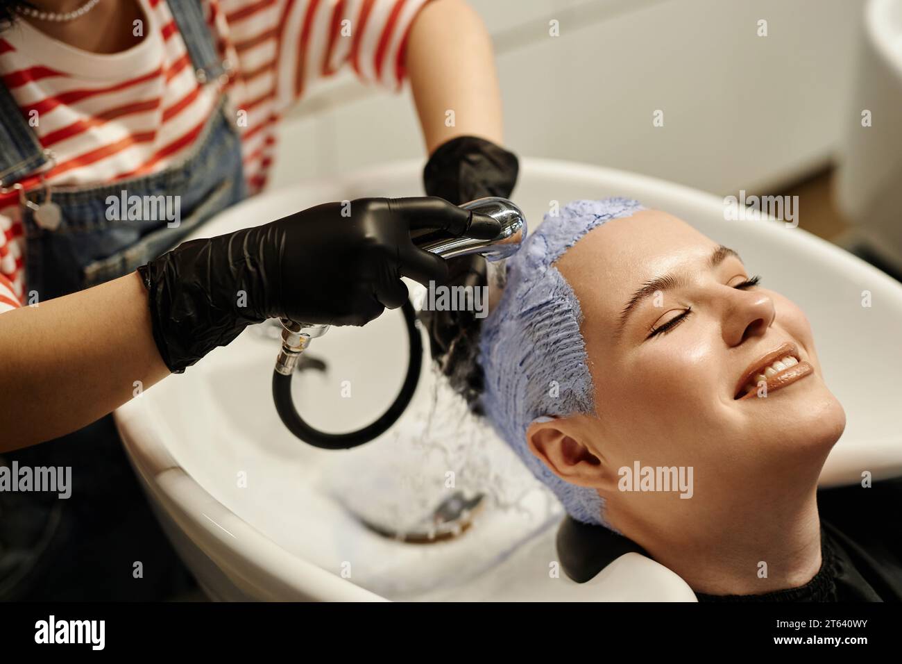 High angle closeup of smiling young woman enjoying hair wash in salon ...