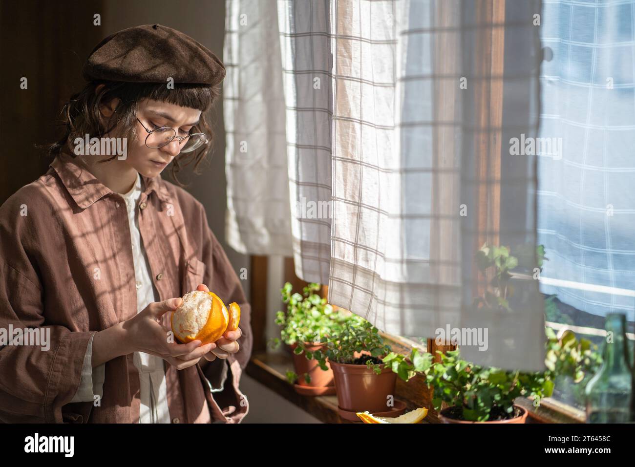 Pensive teenage girl piling orange at home looking like lonely bookworm ...