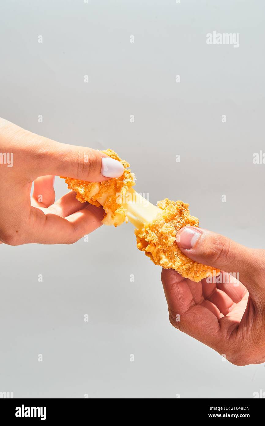 Crispy cheese fried breaded mozzarella cheese sticks stretch two hands ...
