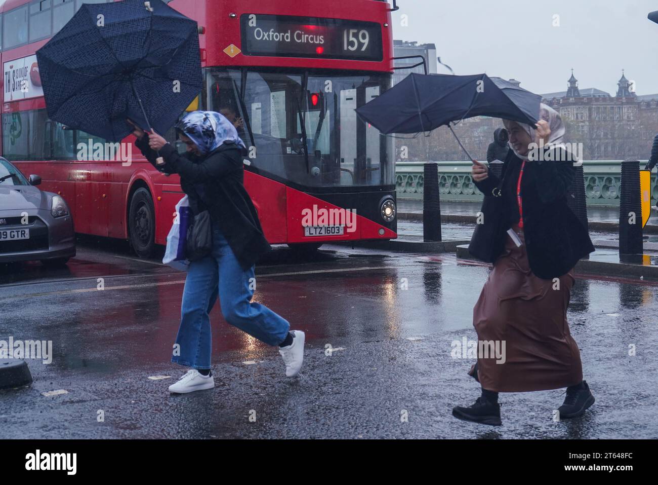 London, UK. 8 November 2023. Pedestrians on Westminster Bridge struggle ...