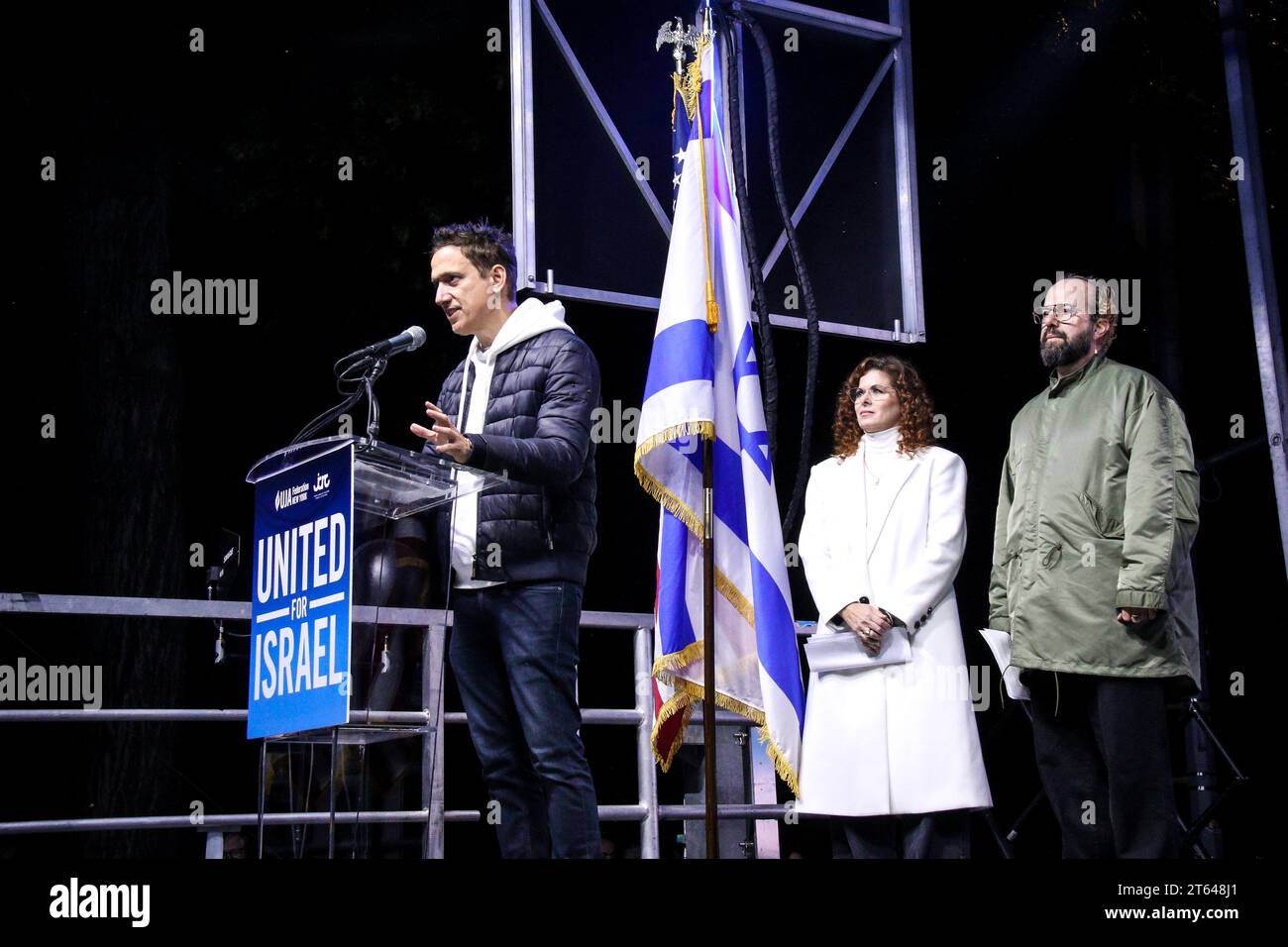 Elon Gold, Debra Messing and Brett Gelman on stage while a family ...