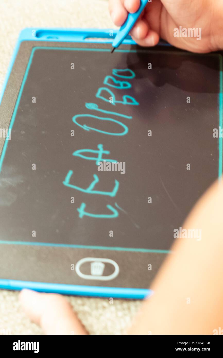 Child drawing with a blue pen on an electronic black board surface ...