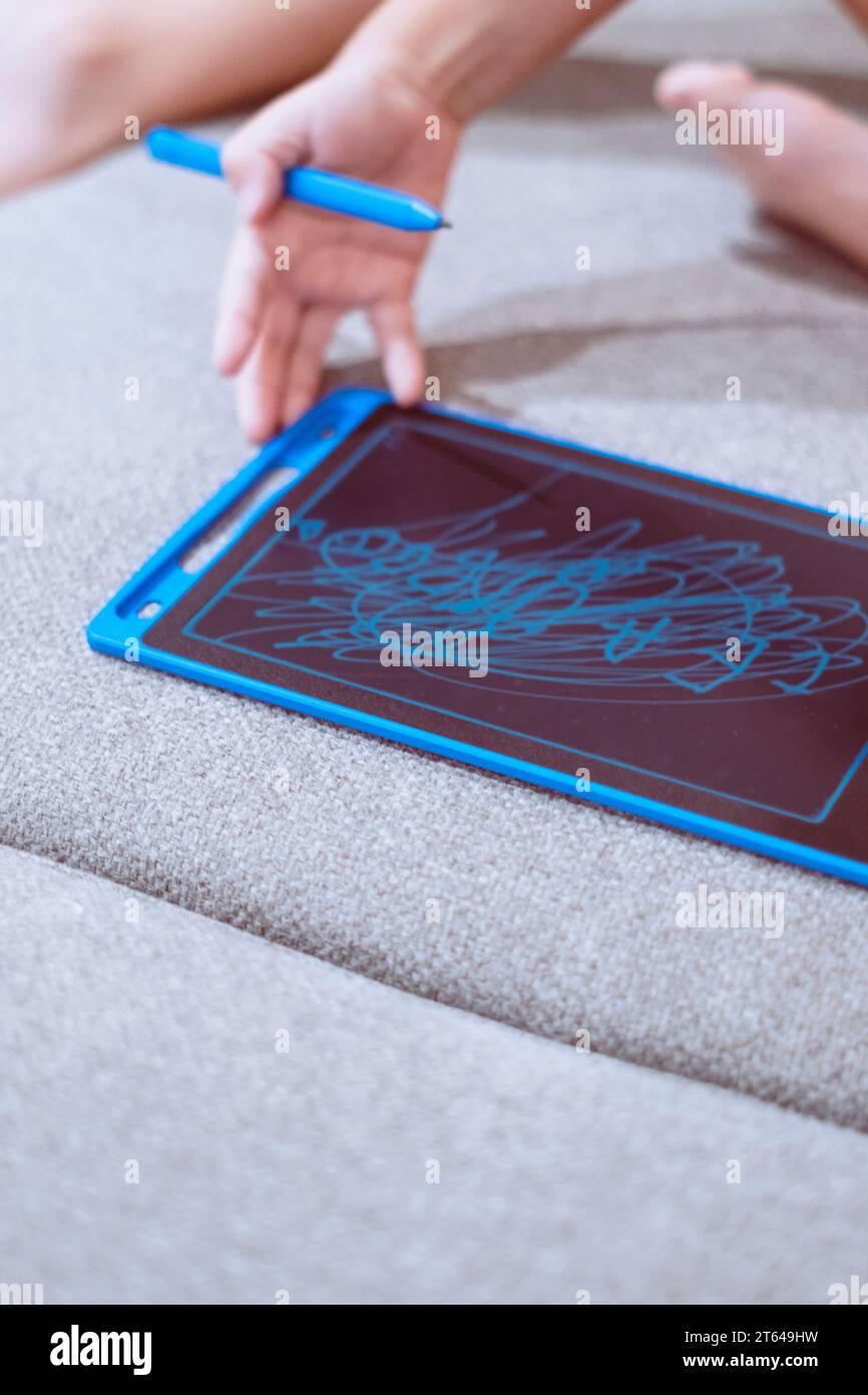 Child drawing with a blue pen on an electronic black board surface ...
