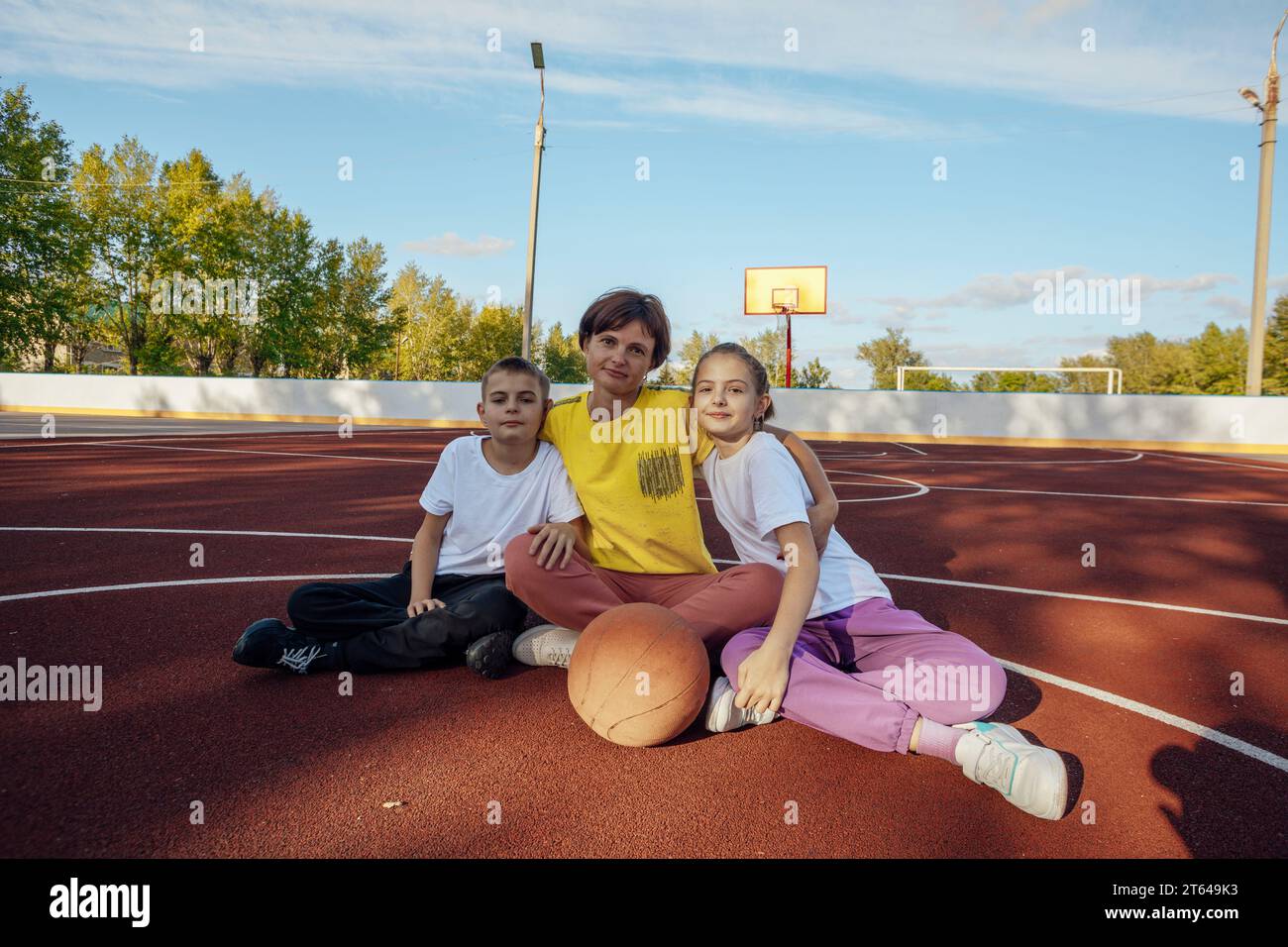 Outdoor hugs: Mother and teenage children cuddle gently in the sun on ...