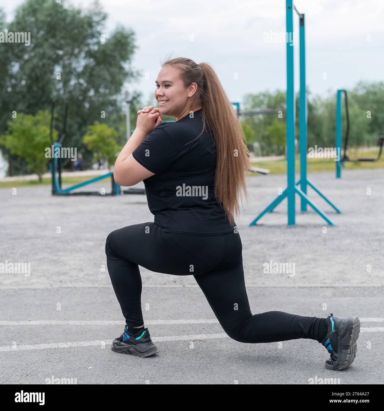 A beautiful fat girl in a black tracksuit is engaged in fitness on the ...