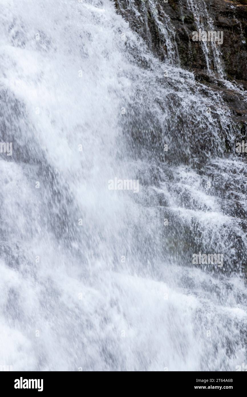 close-up photo of a frothy, white waterfall cascading down a dark ...