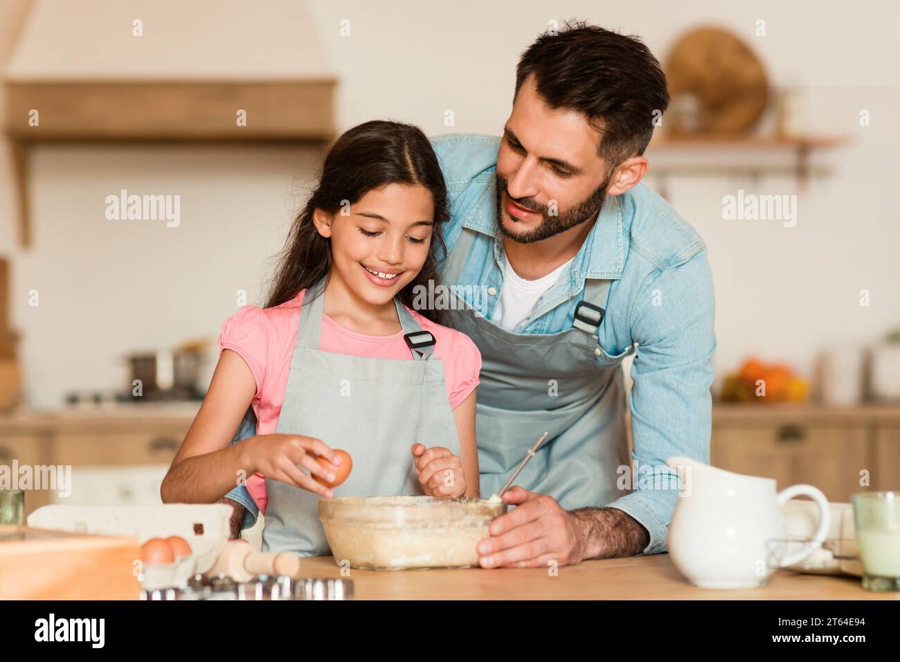 Girl cracking egg with dad's help Stock Photo - Alamy