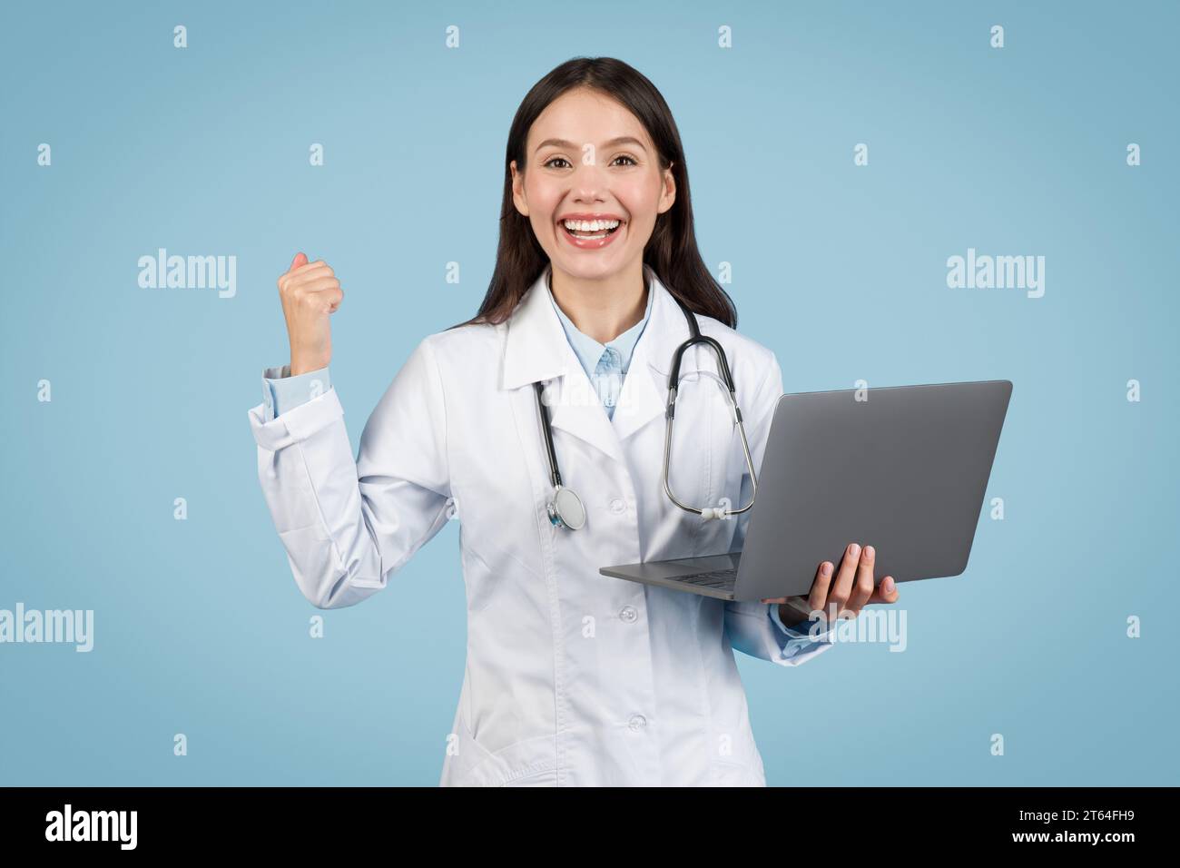Excited doctor with laptop making fist pump Stock Photo - Alamy
