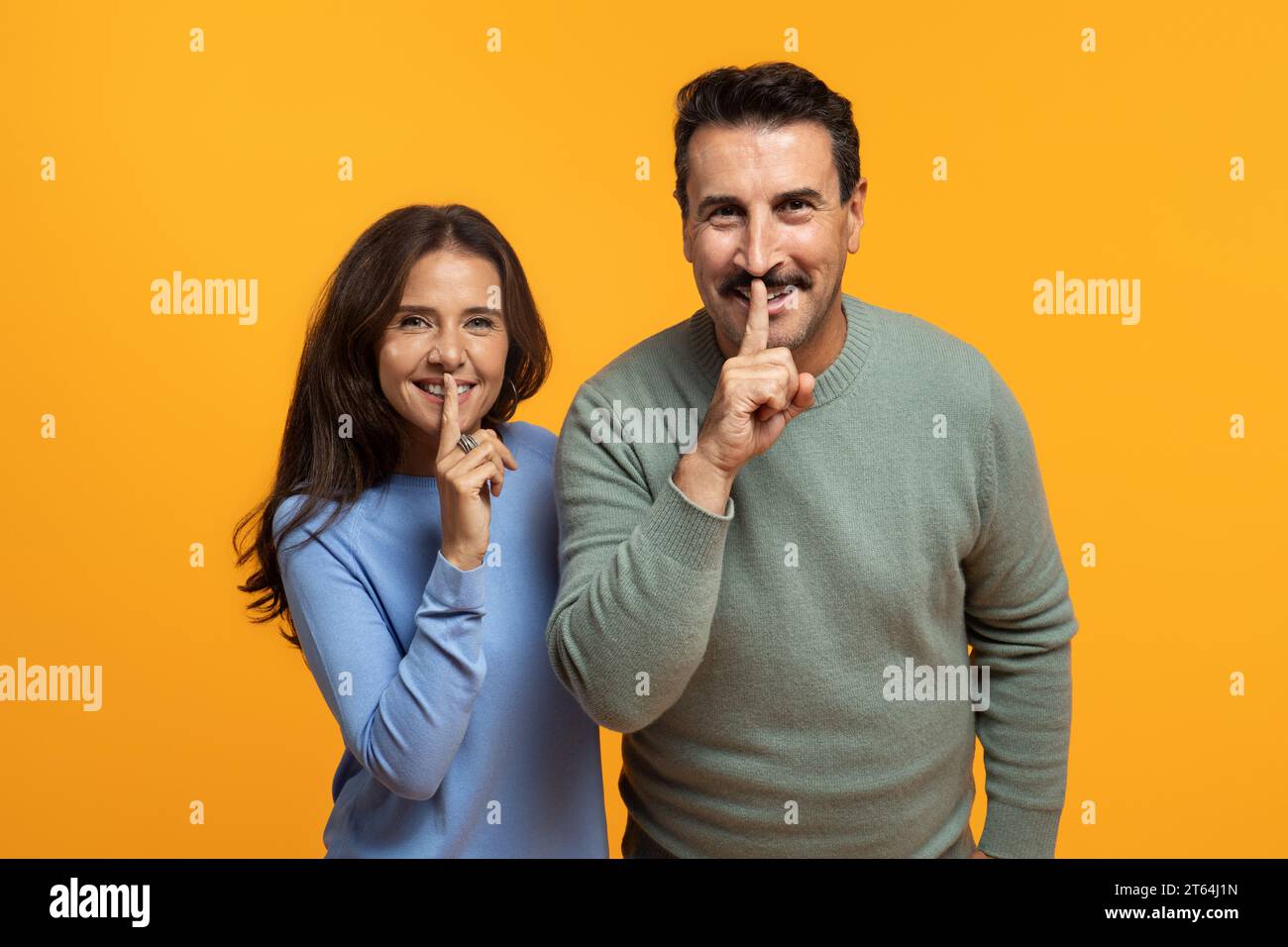 Glad senior european couple in casual put finger at lips, make shh sign ...