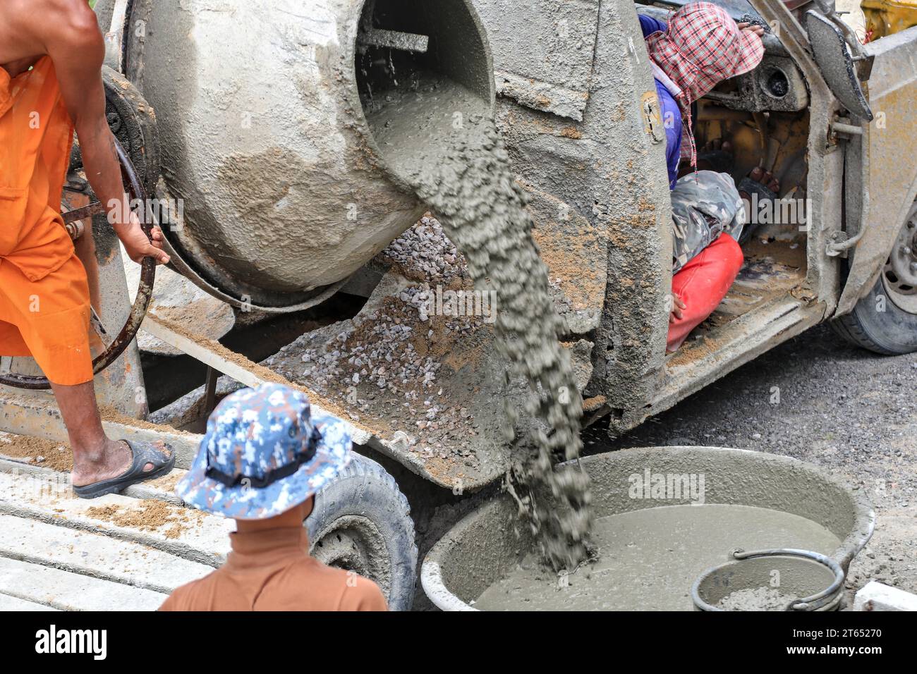 Monks and workers pour ready-mixed concrete into the basin for ...