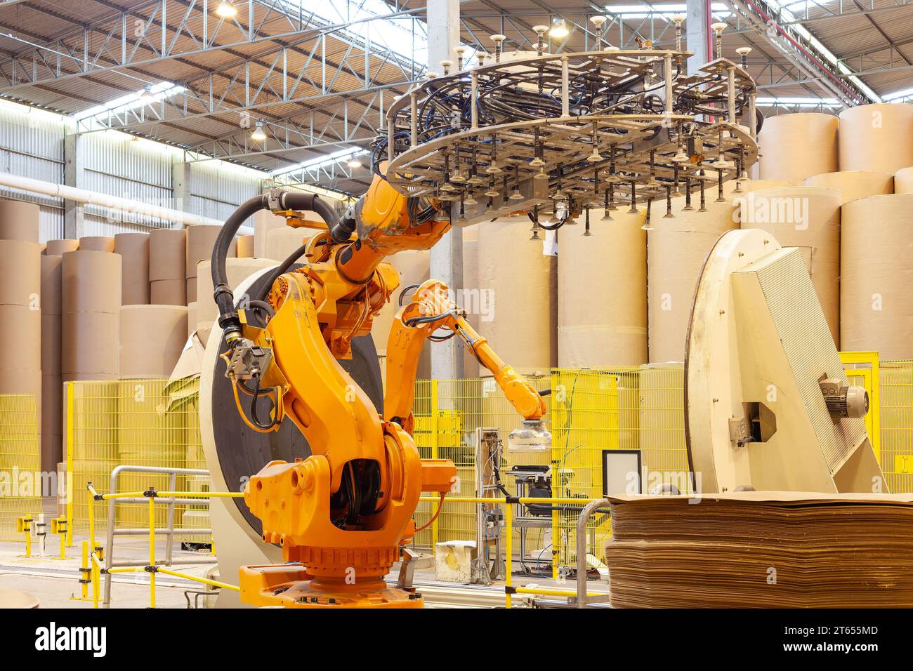 A robotic arm packaging large rolls of paper in a paper mill plant ...