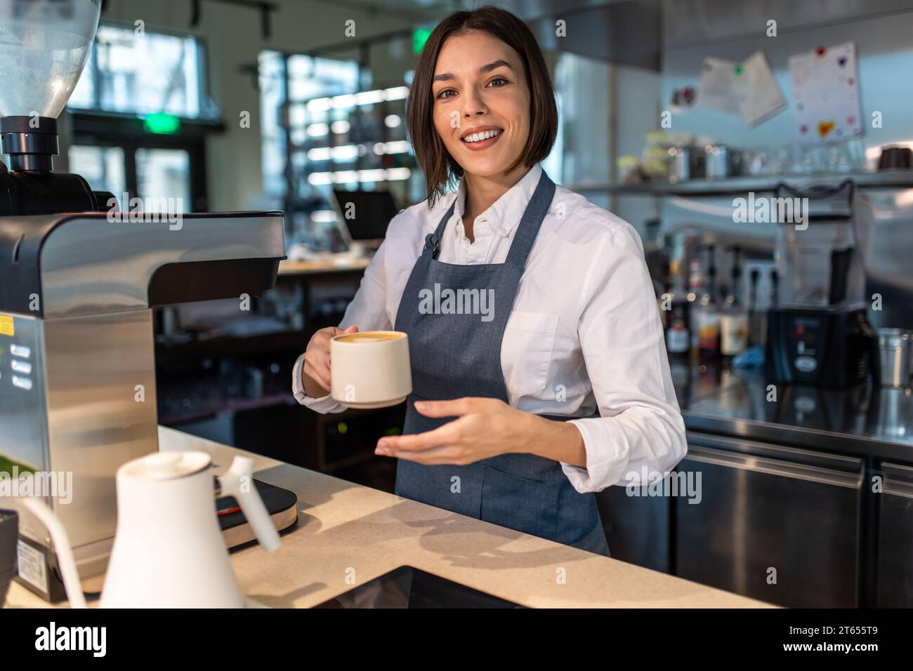 Cute coffee shop assistant holding a coffee cup Stock Photo - Alamy