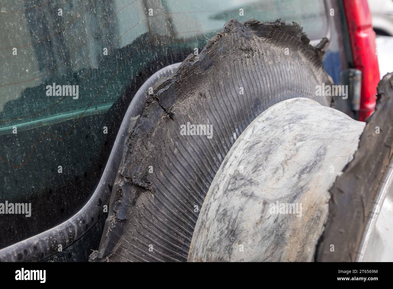 A damaged spare tire hanging on the tailgate of a car. Wheel rim ...