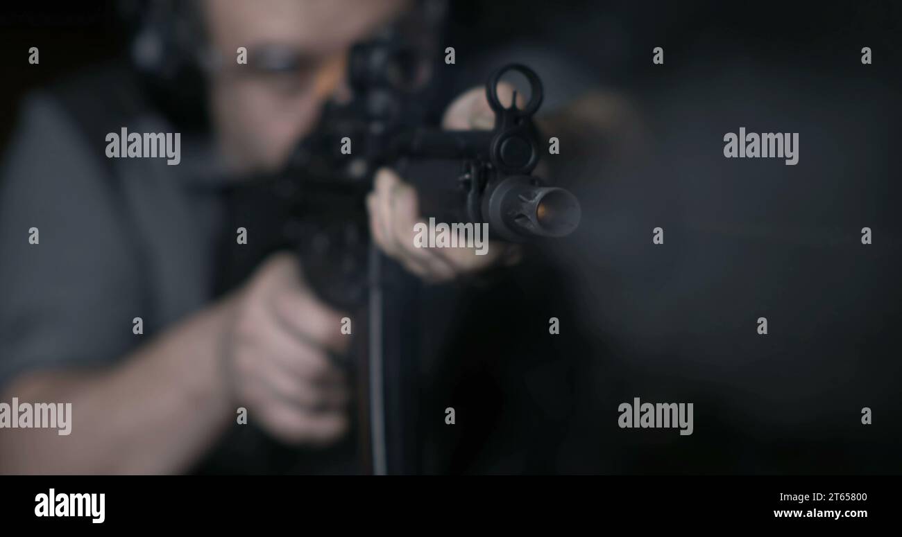 Close-up of man aiming and firing an assault rifle in slow-motion ...