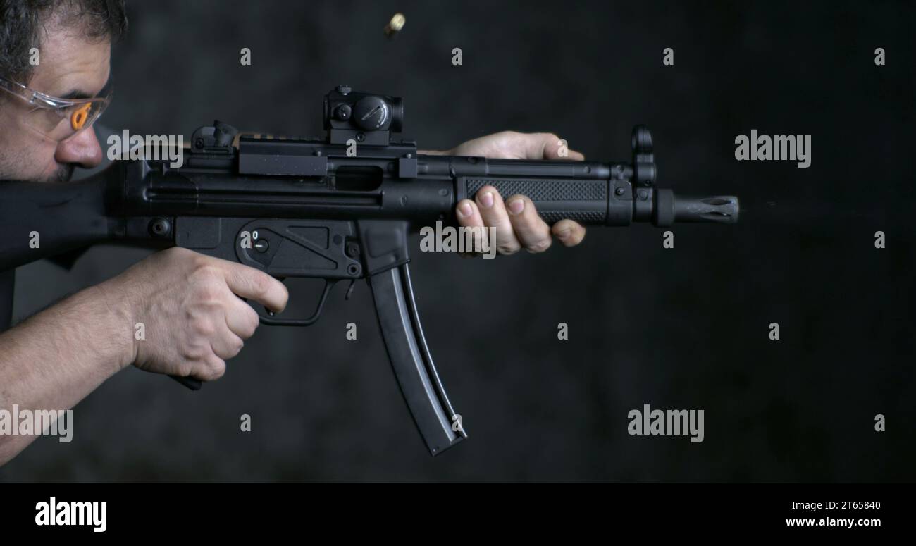 Firing weapon in high-speed, HK SP5K GUN side view. Person aiming and ...