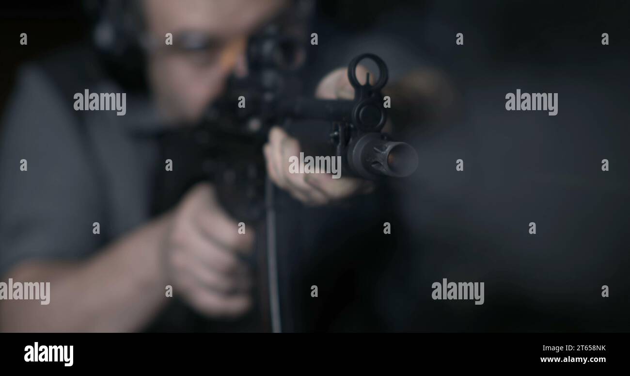 Close-up of man aiming and firing an assault rifle in slow-motion ...