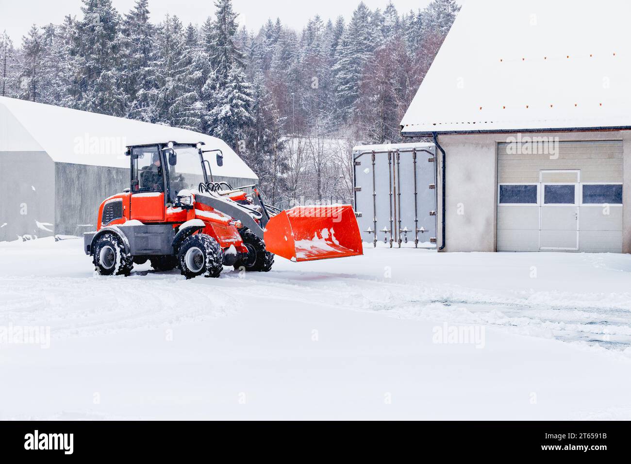 Red tracor cleaning snow in snowstorm. Blizzard weather conditions ...