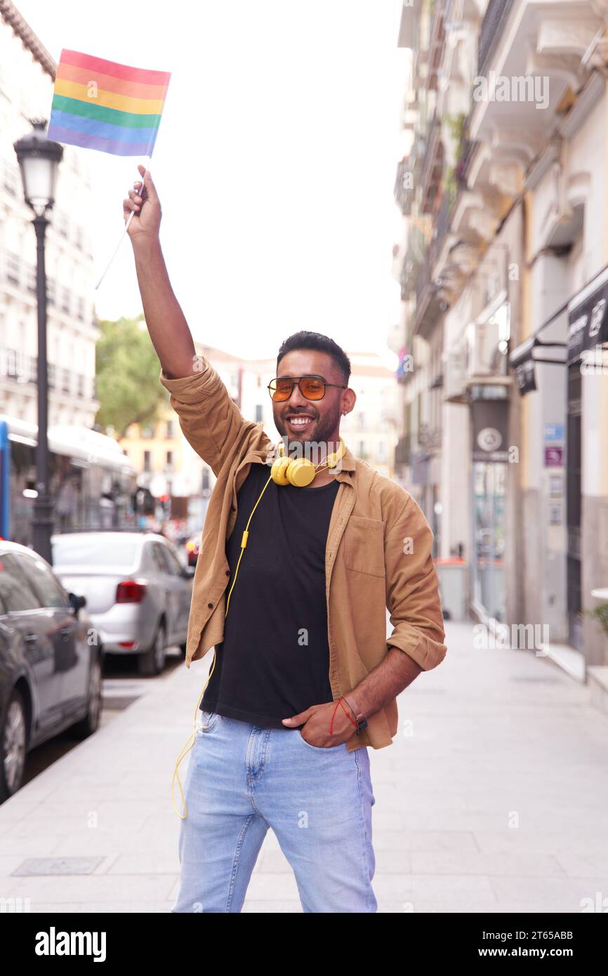 young latin man in casual clothes raising a lgbt flag claiming the ...