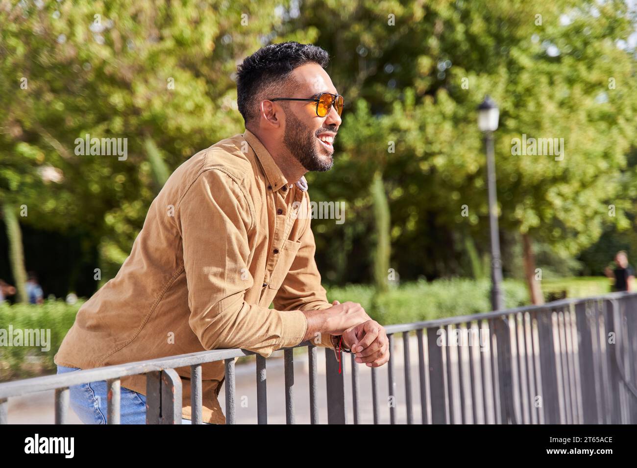 Smiling man leaning on a railing. young latino man with sunglasses and ...
