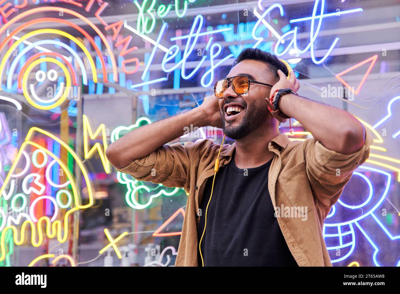 Portrait of young latino boy with neon light reflection on his face ...