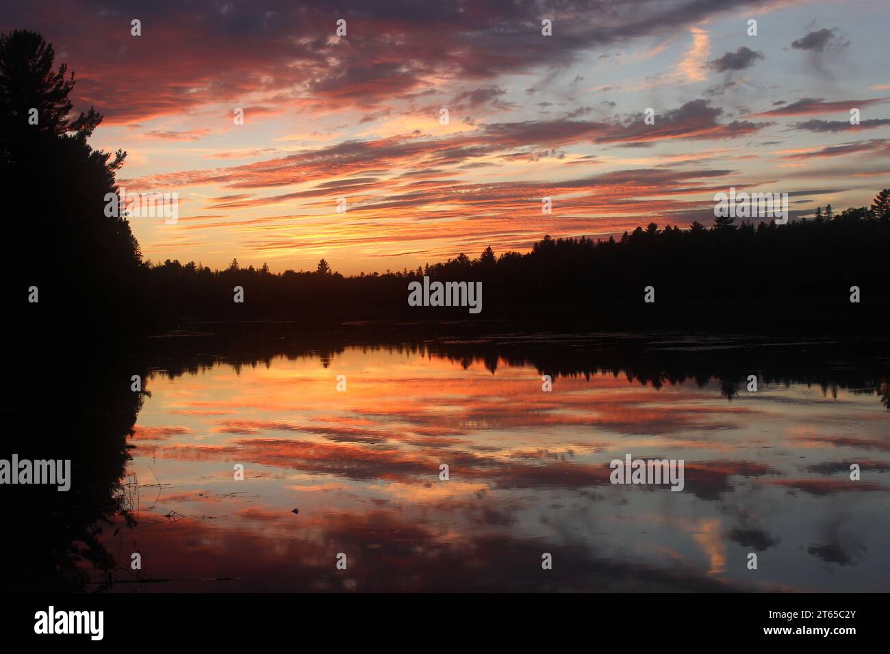 An autumn sundown reflected on a still river in Michigan's Upper ...