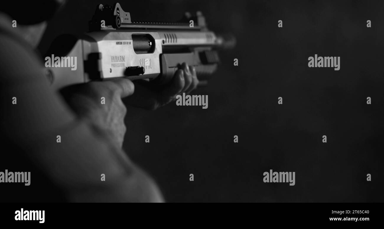 Monochrome shot of person firing a powerful shotgun and reloading shell ...