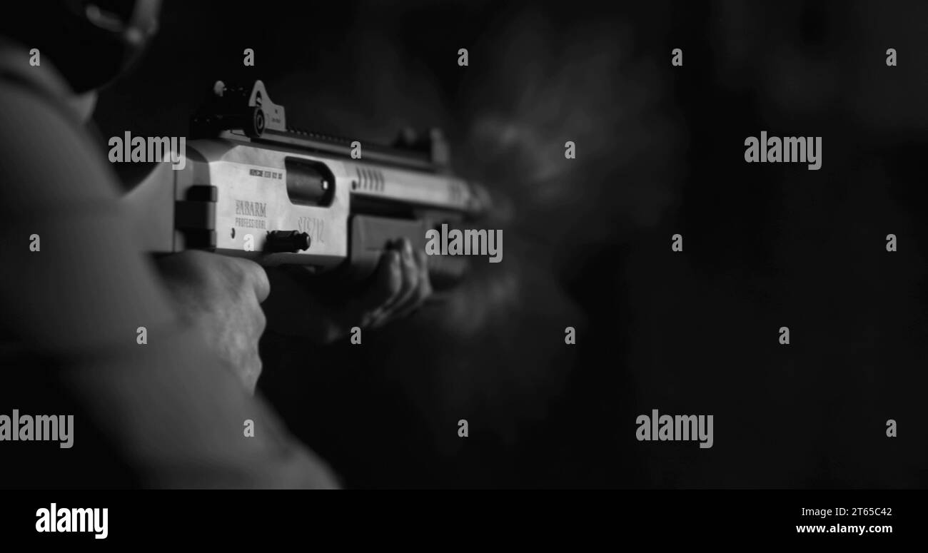 Monochrome shot of person firing a powerful shotgun and reloading shell ...