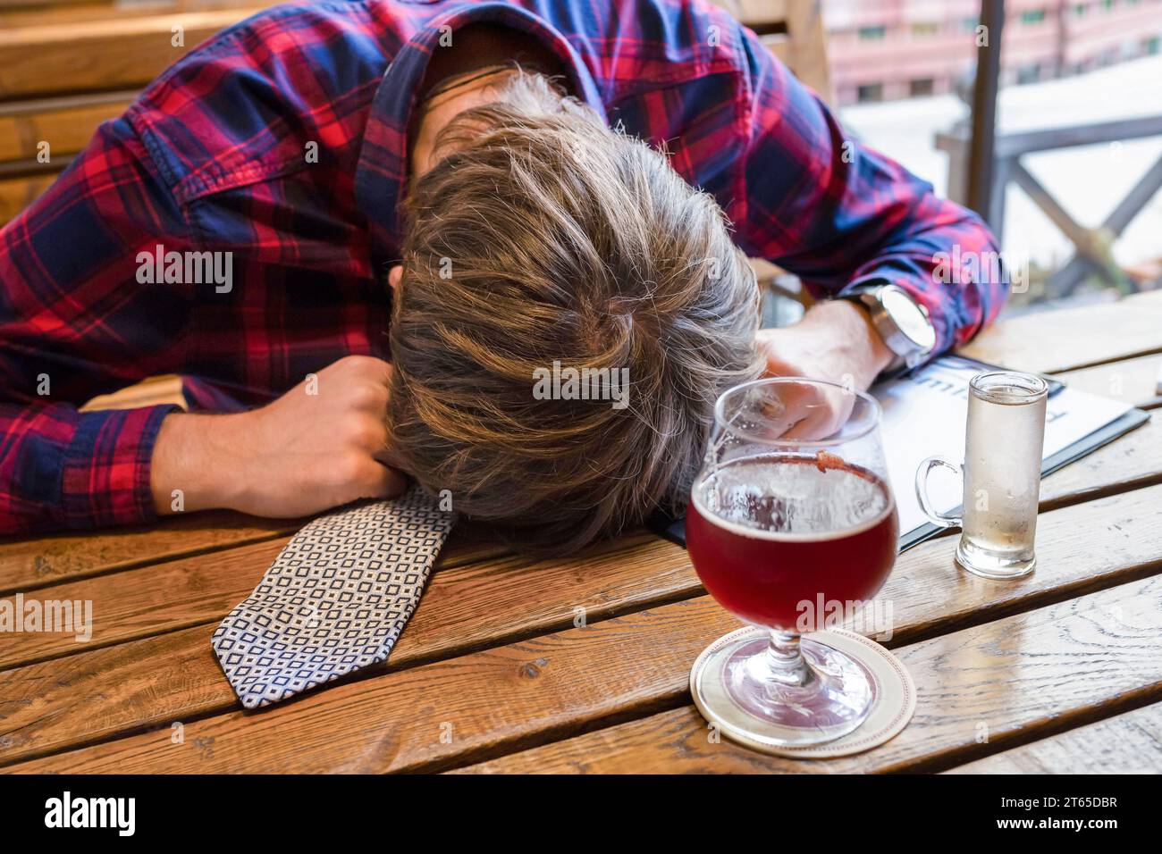 Young man drinking alcoholic lying or sleeping on the table in the bar ...