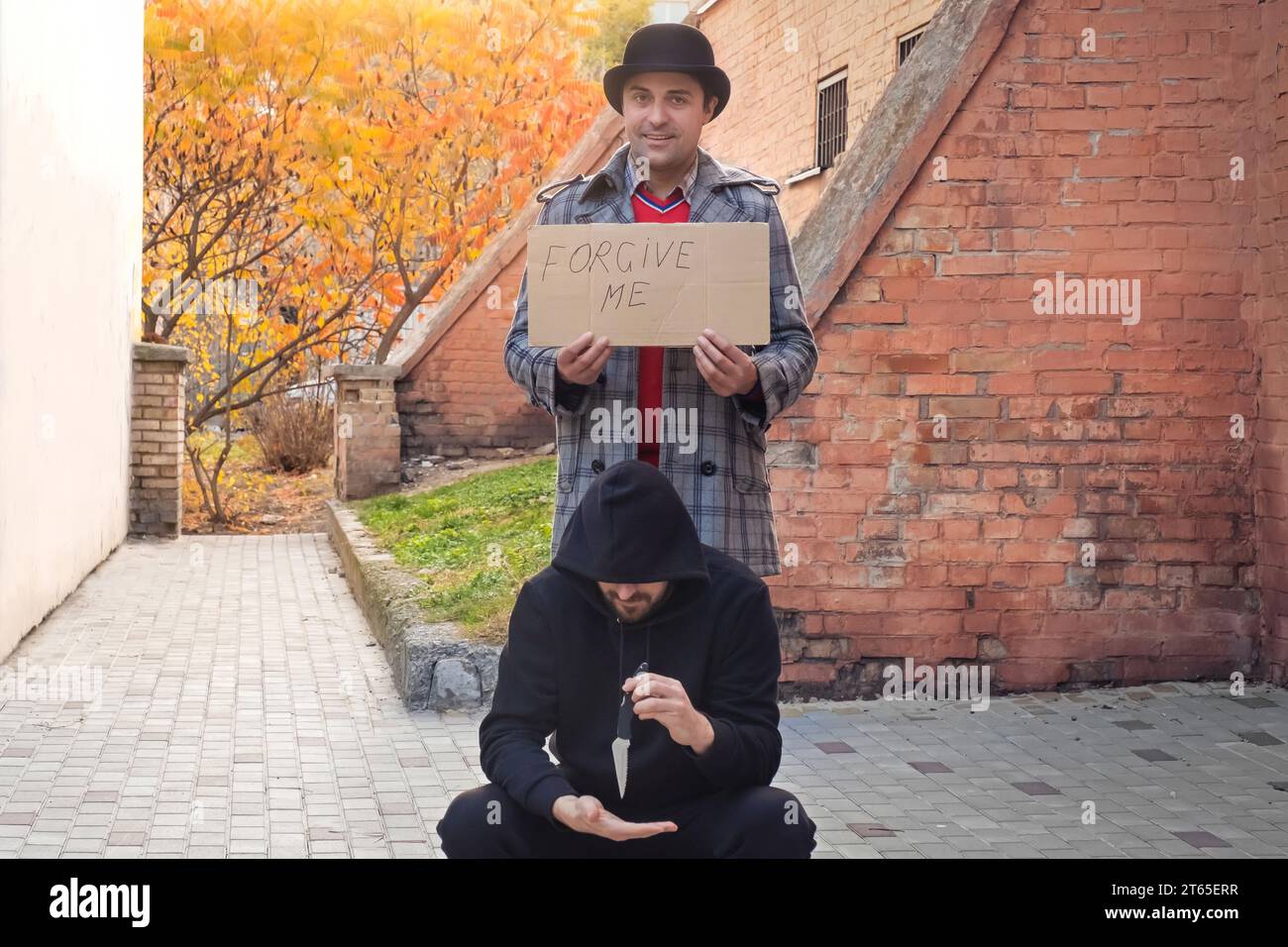 Forgiveness concept. Men holding a sign saying forgive me on a city ...