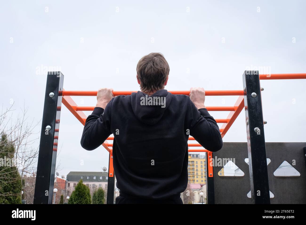 Conportative young man making pull-up exercises on the crossbar ...