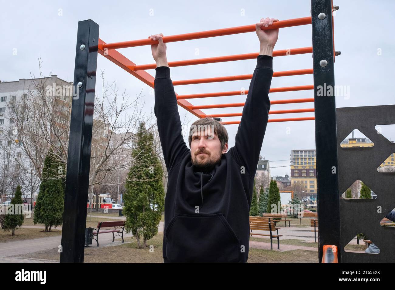 Young man making pulling exercises at the crossbar at the city ...