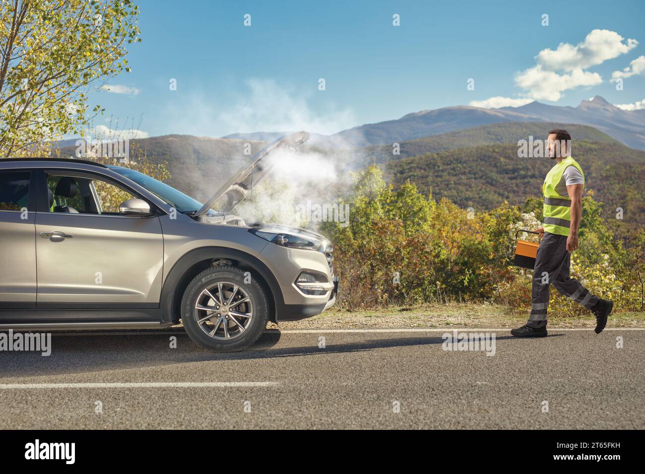 Road help worker with a tool box walking towards a vehicle with an open ...