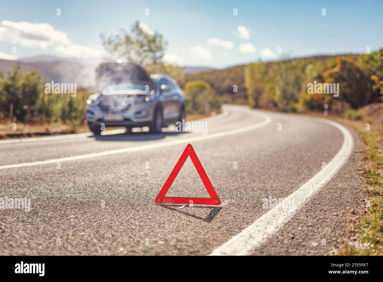 Red warning triangle on open road in front of a SUV with an engine ...