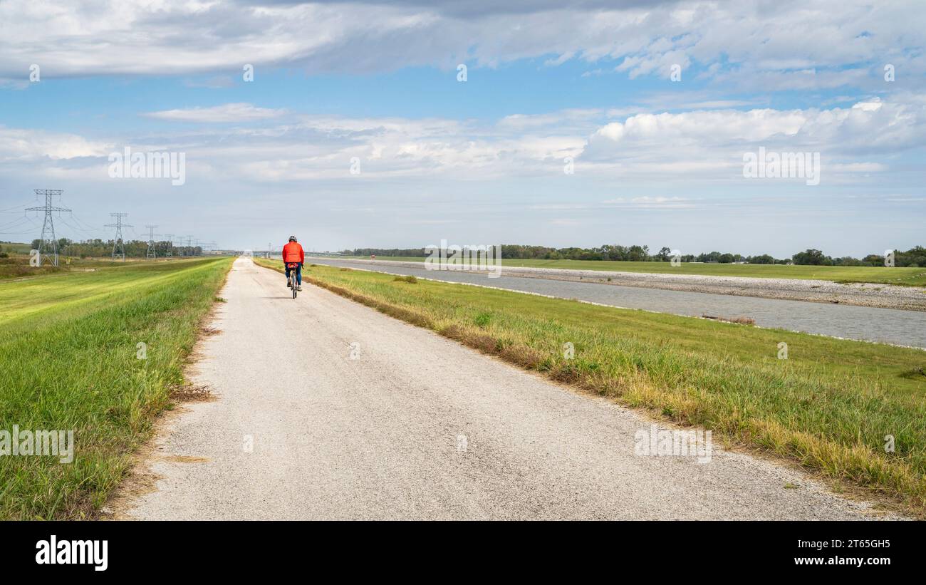 lonely cyclist is riding a gravel touring bike - biking on a levee ...