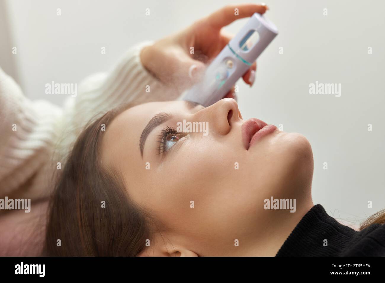 cosmetologist using primer spray for eyelash extension procedure in ...