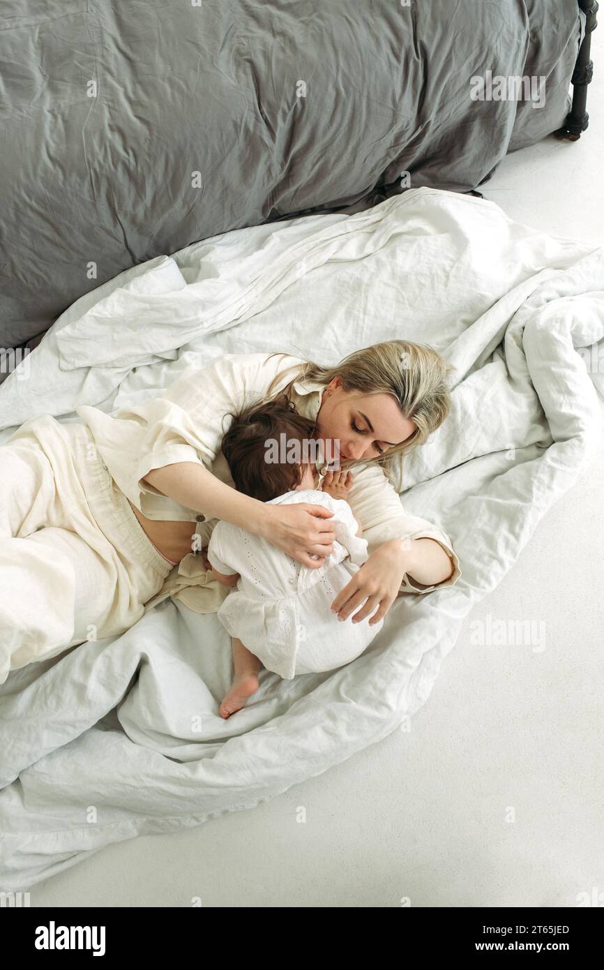 The little girl lay down on her mother and wants to sleep. Mom tenderly ...