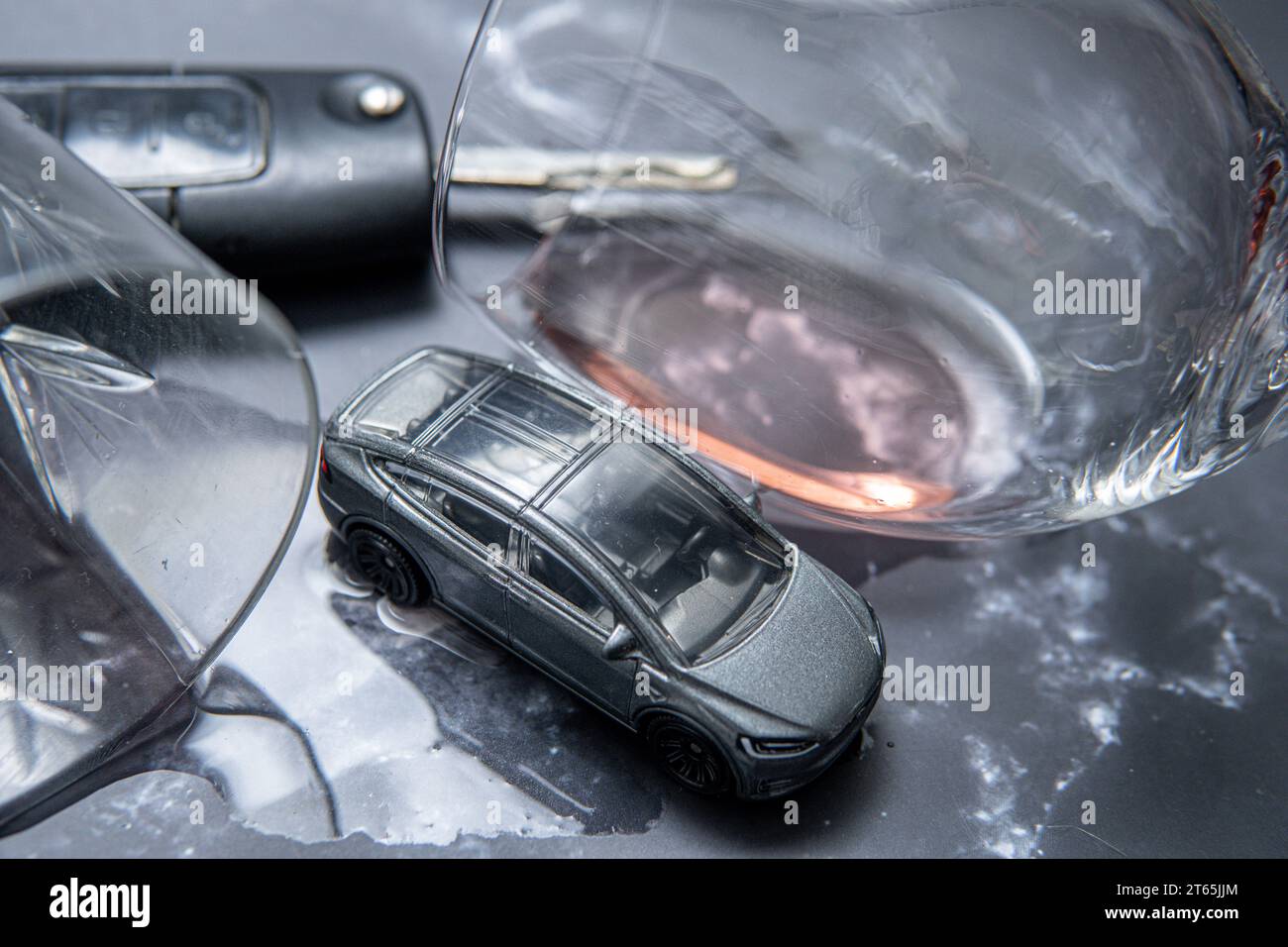 concept showing drunk driving. A toy car next to alcohol glasses ...