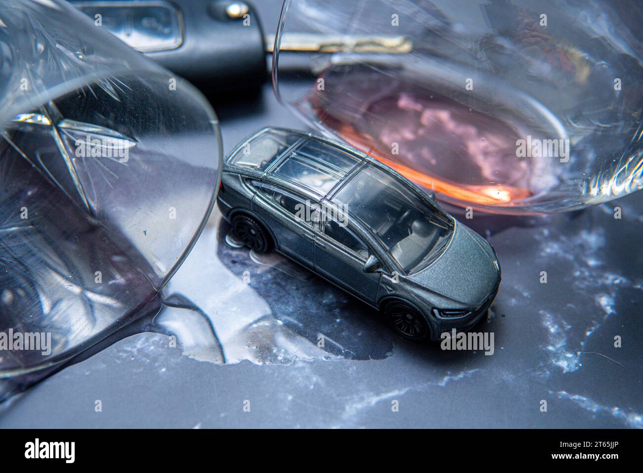 concept showing drunk driving. A toy car next to alcohol glasses ...