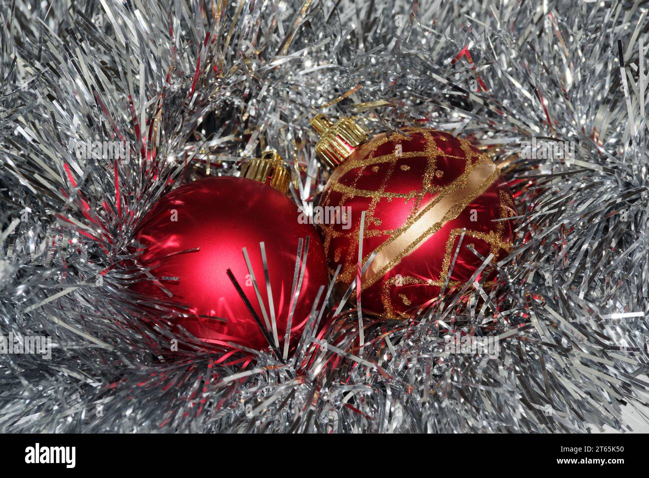 Two red Christmas baubles lying in the silver tinsel Stock Photo - Alamy