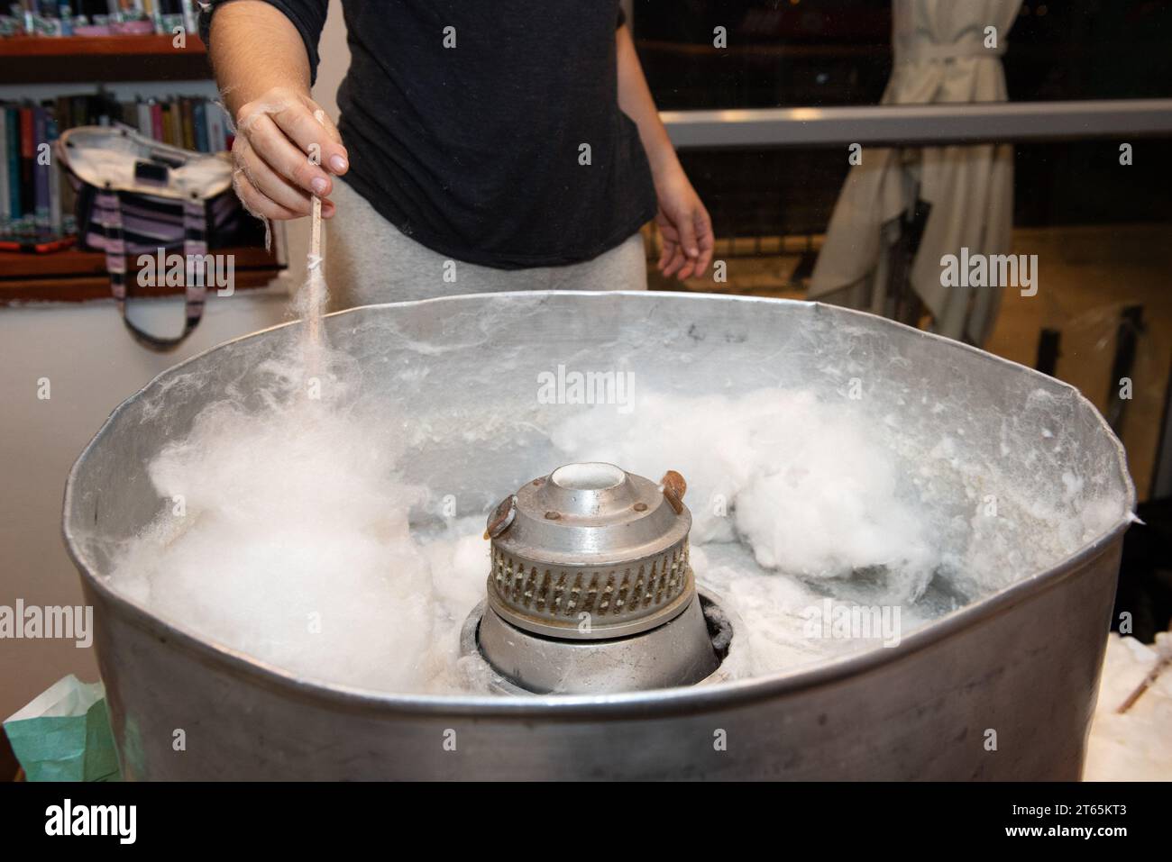White cotton candy or spun sugar is collected on a paper holder at a ...