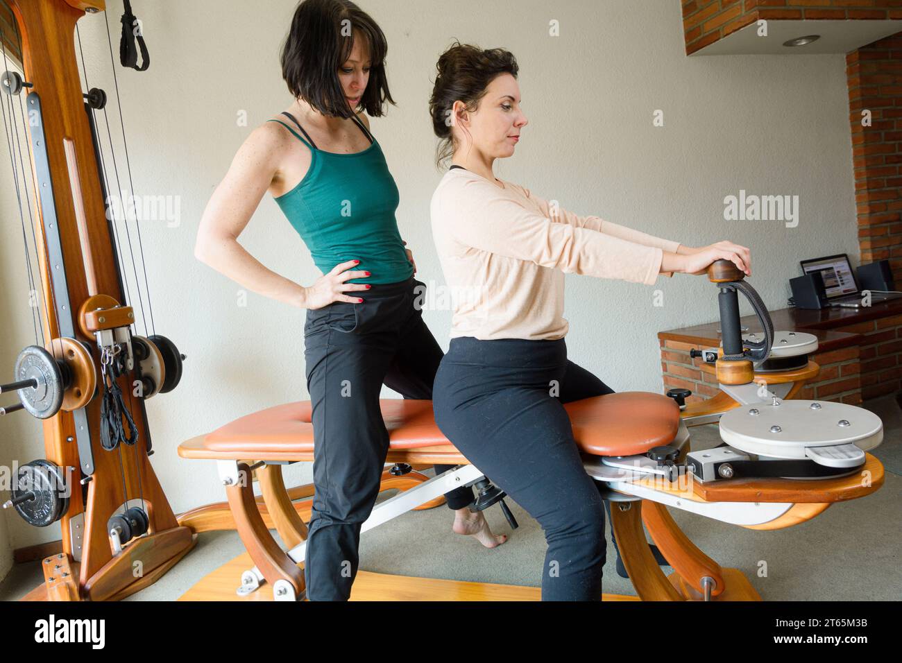 Caucasian adult female gyrotonic instructor teaching female student at ...